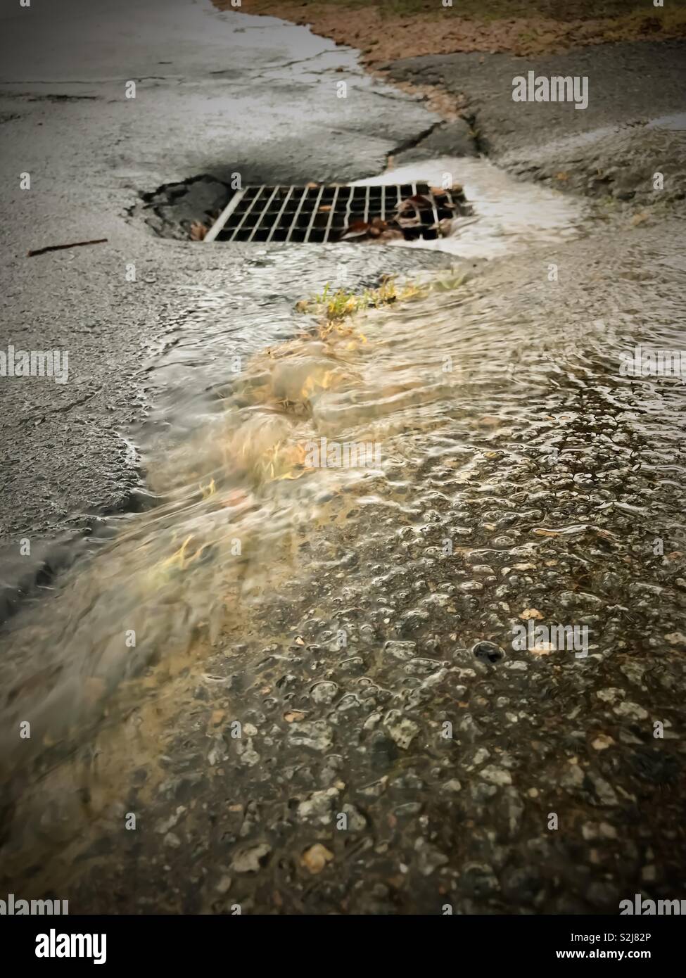 Rivulet flows to storm drain Stock Photo - Alamy