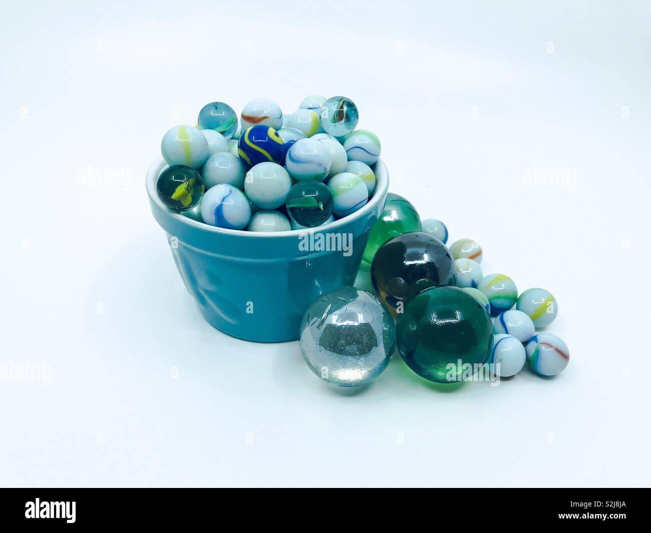 Lots of marbles in a blue pot and around Stock Photo - Alamy