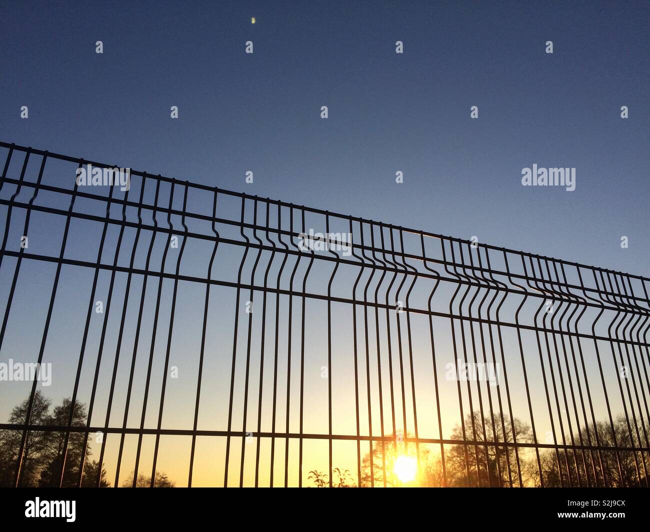 Metallic fence and sunset Stock Photo - Alamy