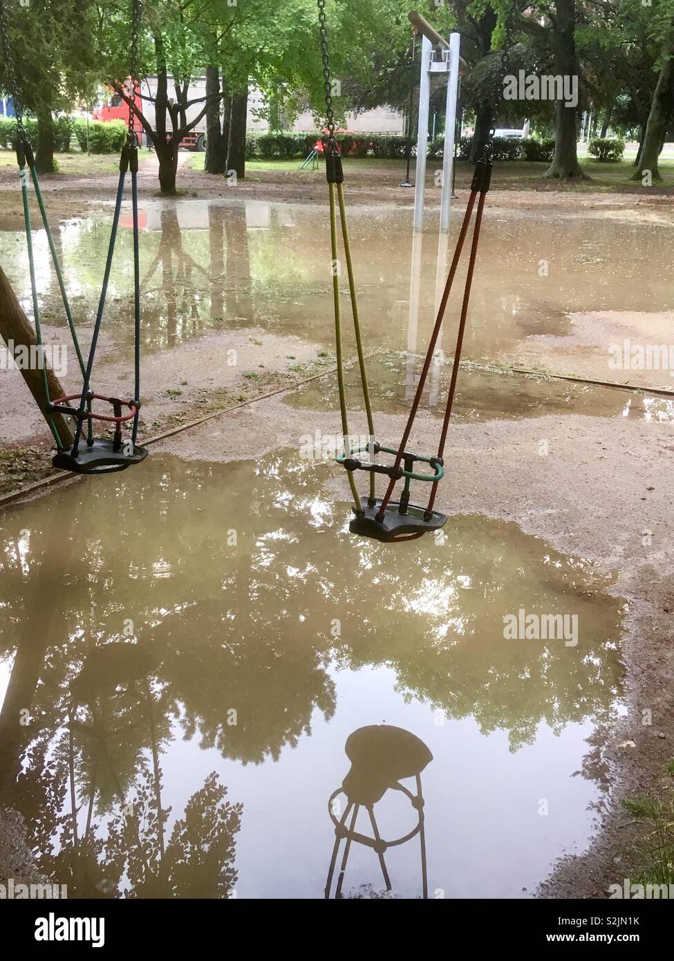 Swings at playground over deep pools of heavy rain Stock Photo - Alamy
