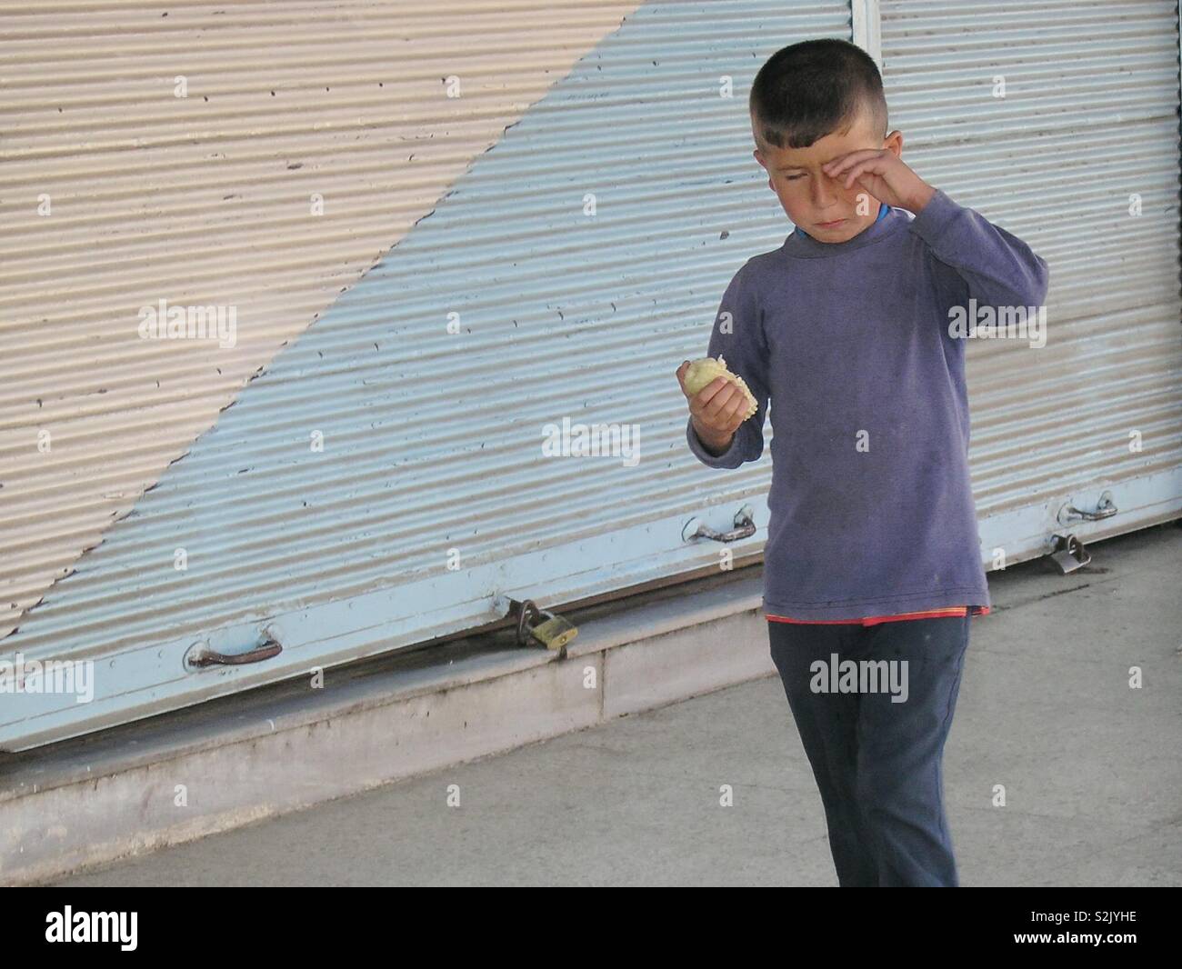 Poor boy eats on the street Stock Photo - Alamy