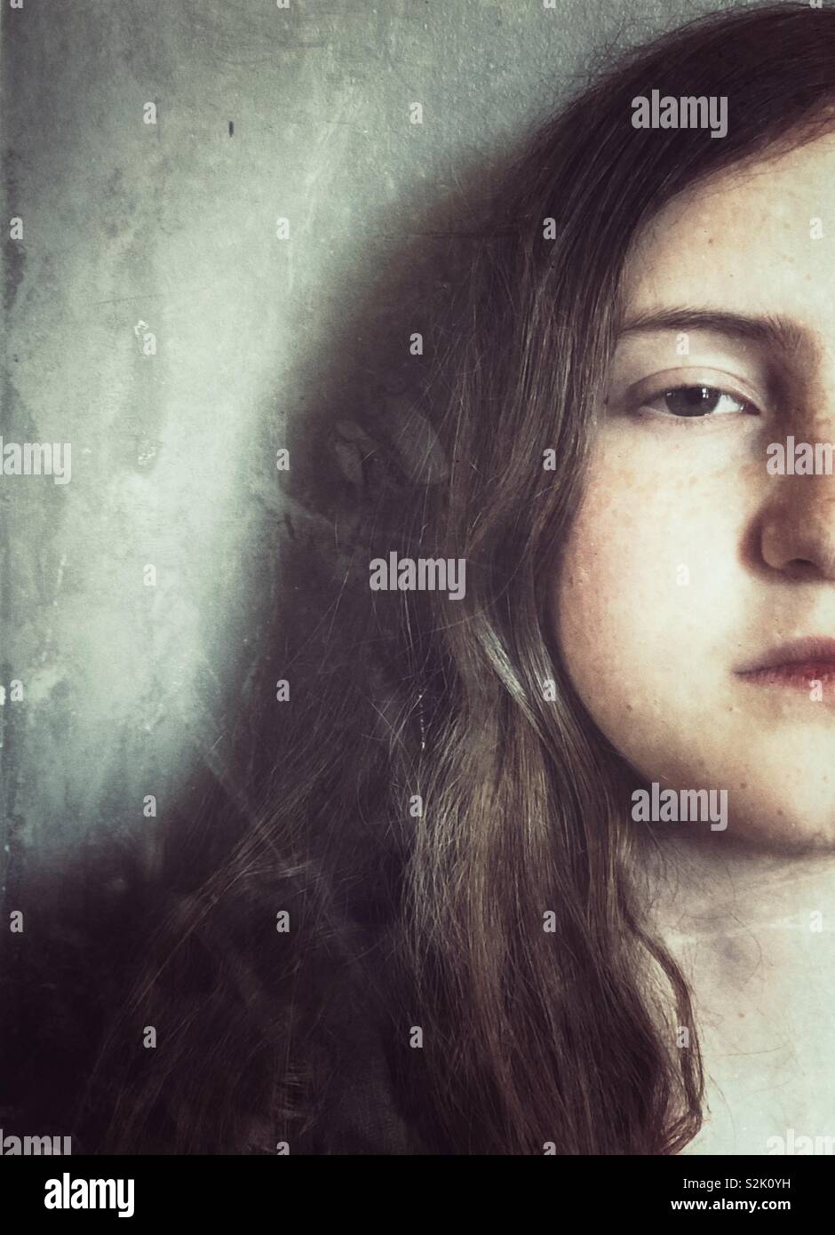 Creative portrait of teenage girl half face with serious expression ...