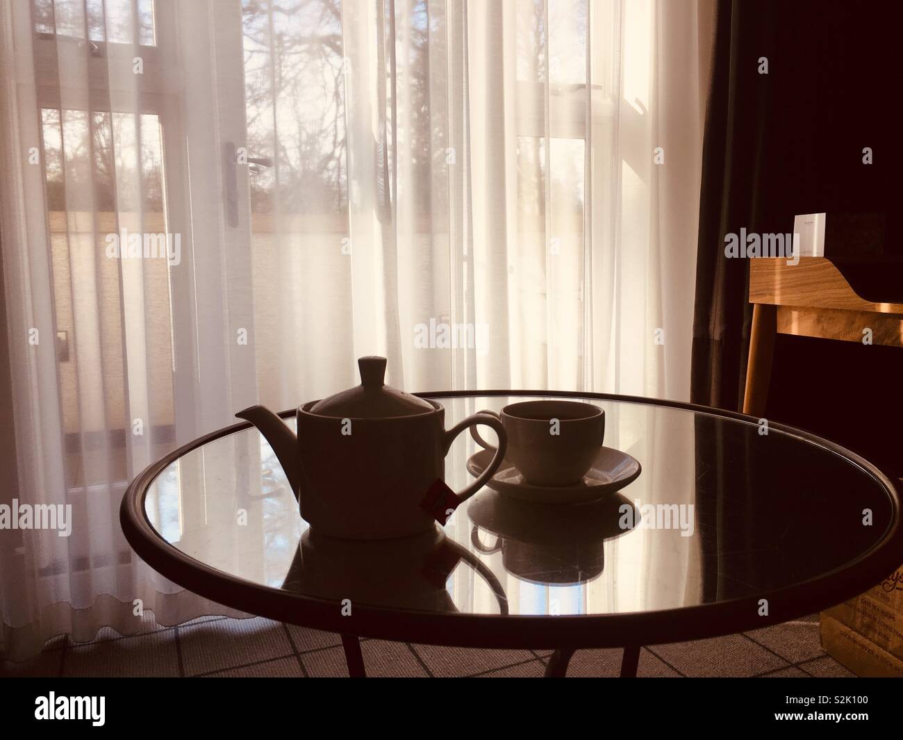 Afternoon tea with cup saucer and tea pot on a glass table during a ...