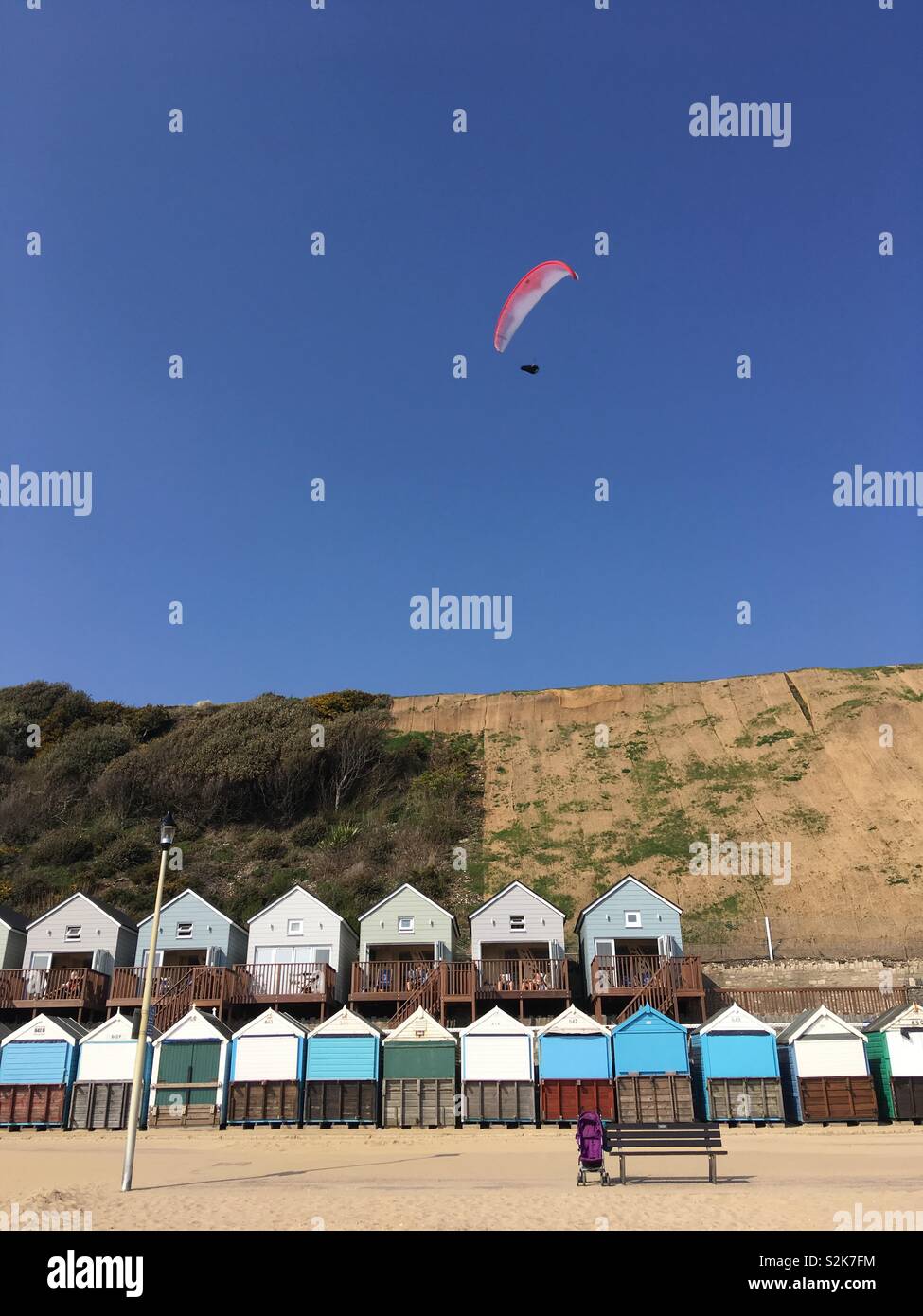 Boscombe beach near Bournemouth under a blue sky. Handglider soaring ...