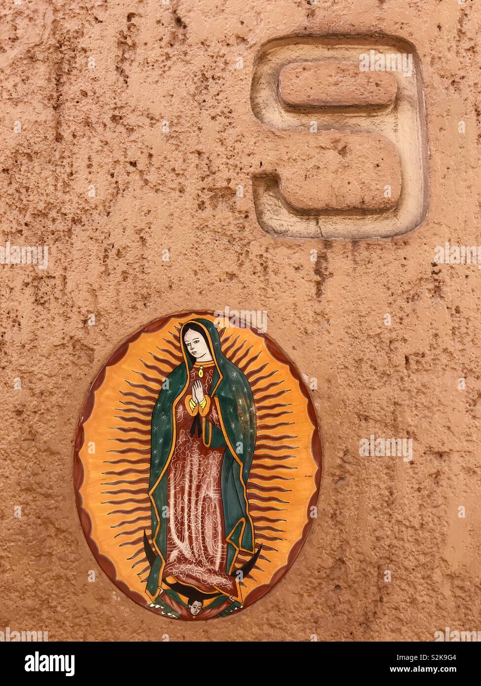 A number nine and an image of Our Lady of Guadalupe in an orange wall ...