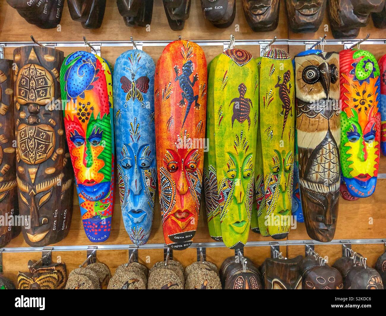 A row of colourful wooden handcrafted masks hanging in a souvenir shop ...