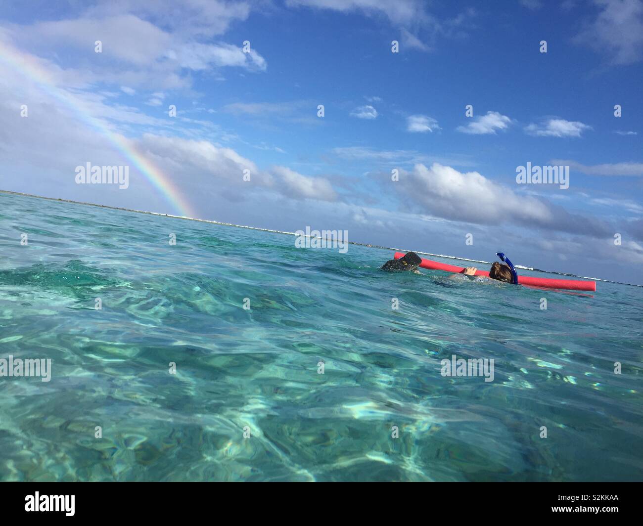 Woman floating in ocean below rainbow, Cook Islands Stock Photo - Alamy