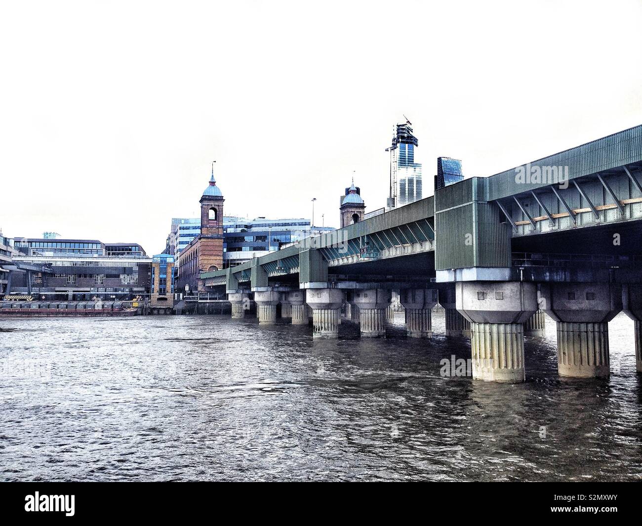 A view across the River Thames showing the railway bridge leading to ...