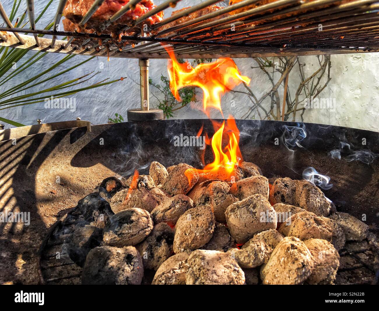 Barbecue flames lick at the sausages and burgers Stock Photo - Alamy