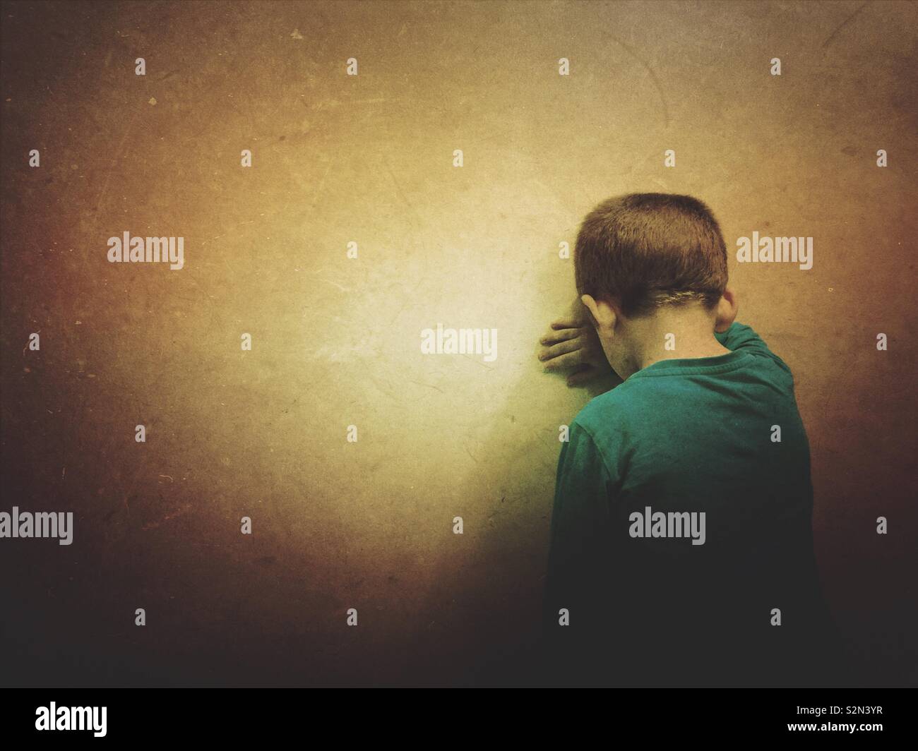 Sad little boy hiding his face against the wall Stock Photo - Alamy