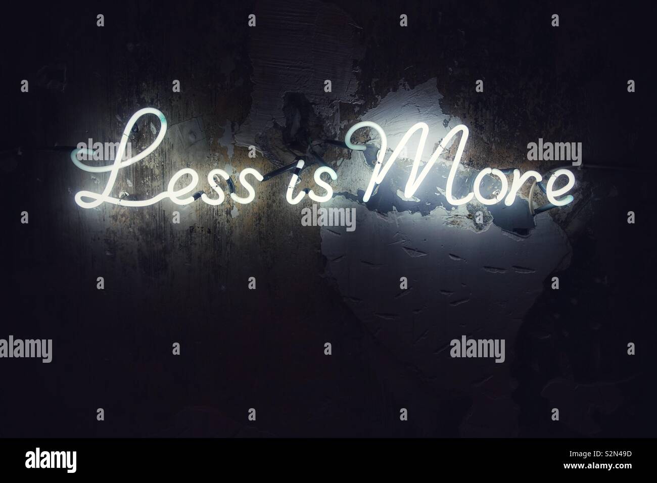 Neon lettering: Less is More. White letters on a rough brick and ...