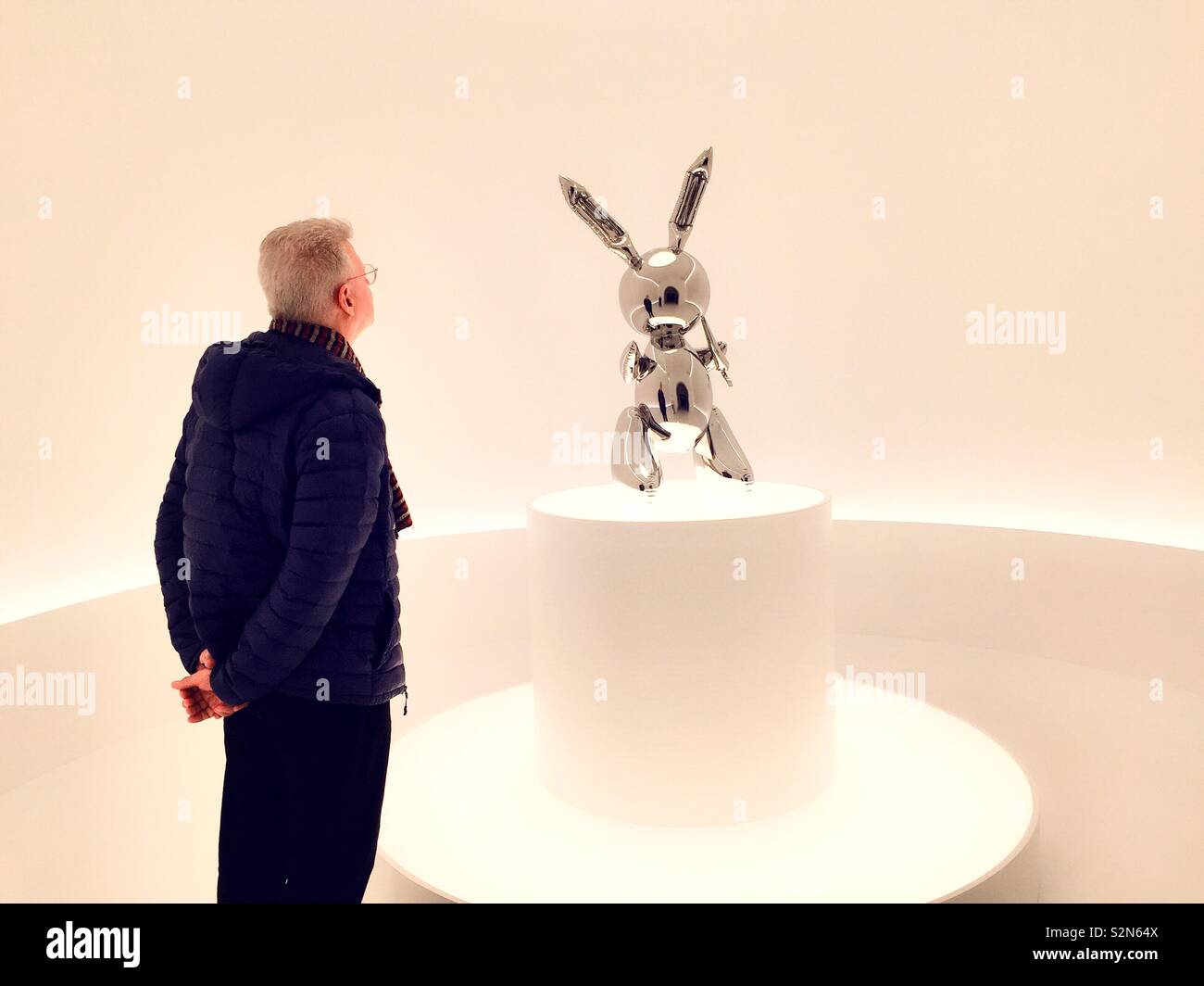 Male patron views Jeff Koons sculpture of a metallic rabbit during pre ...