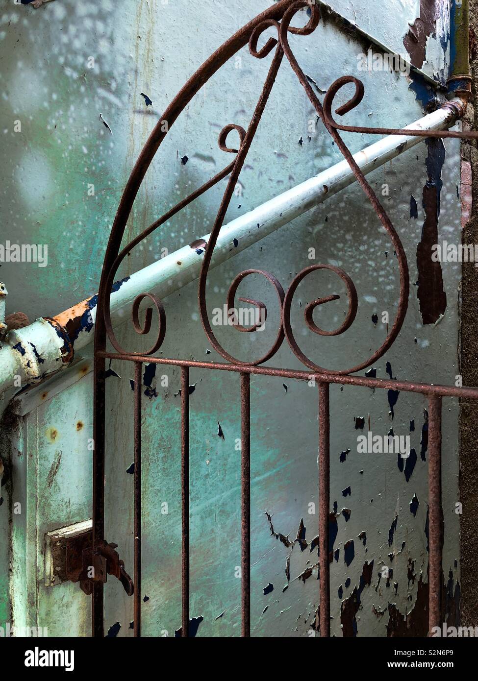 Rusty wrought iron gate leading to a scruffy alley Stock Photo - Alamy