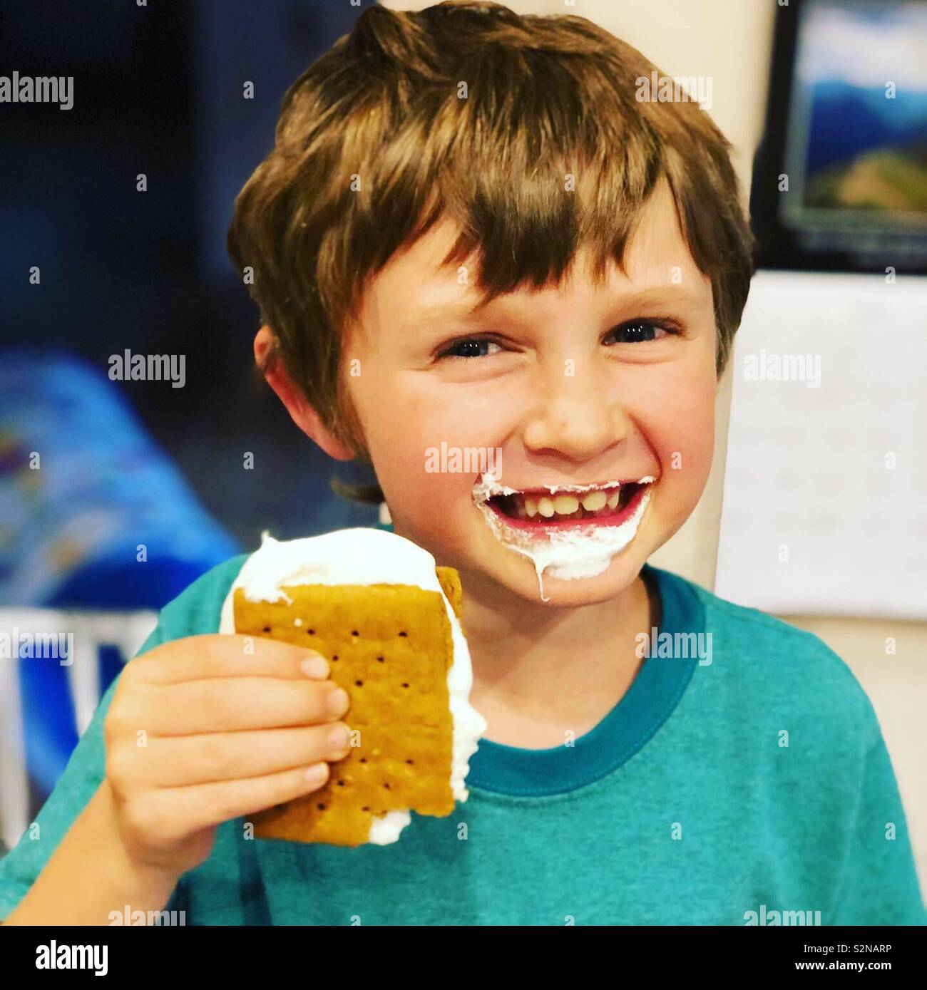 Cute, young, smiling boy eating a S’mores dessert with marshmallow on ...