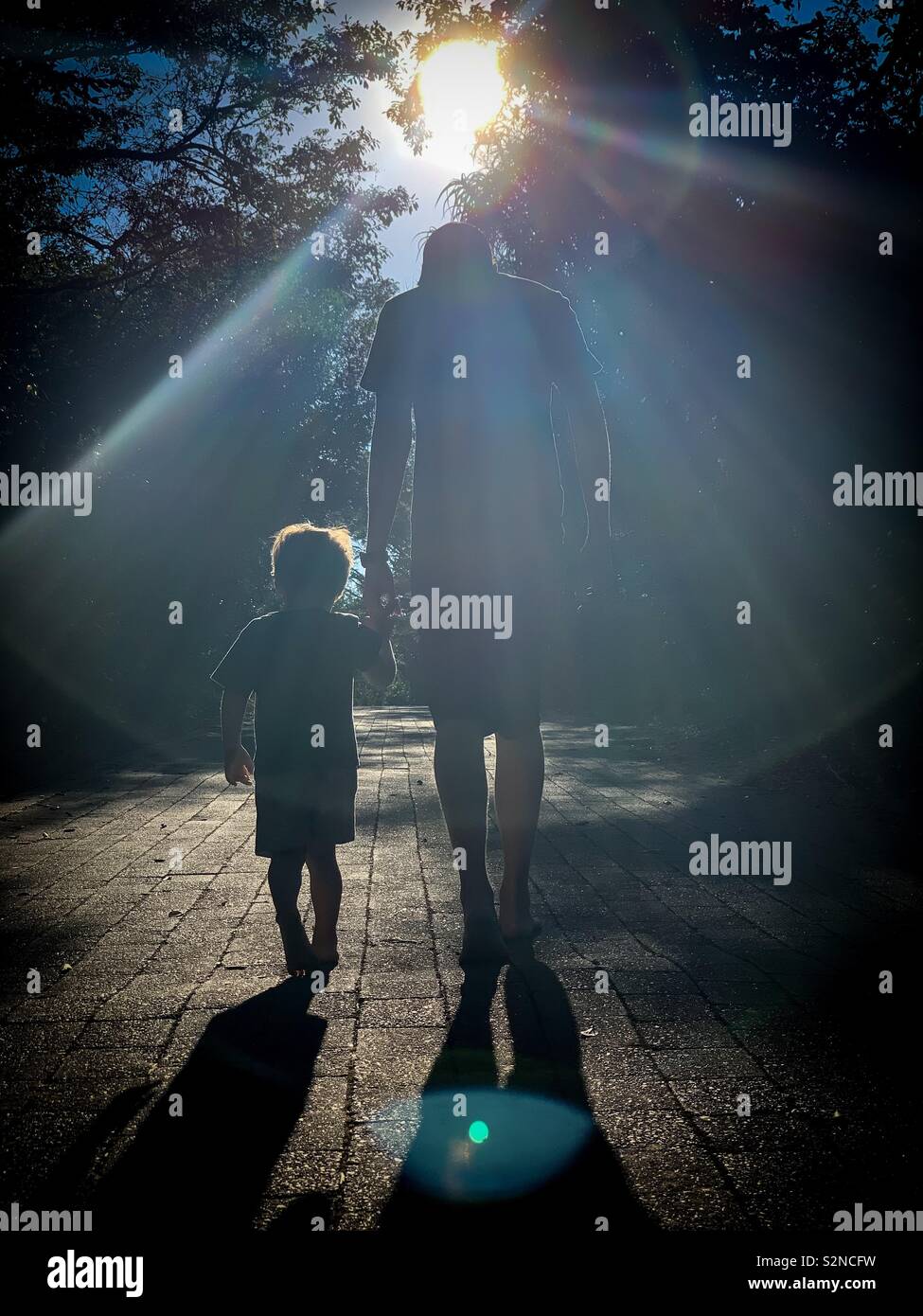 Father and sun walking down a road Stock Photo - Alamy
