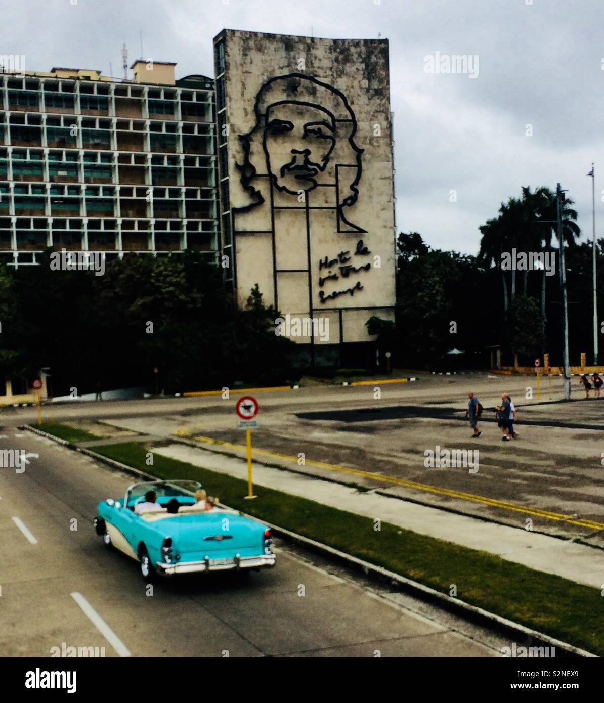 A classic American car driving past a huge memorial to Che Guevara in ...