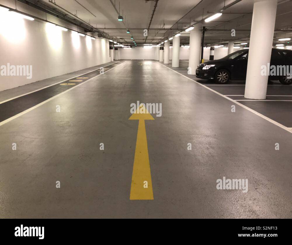 A yellow arrow marks the way to go on the floor of an underground car ...