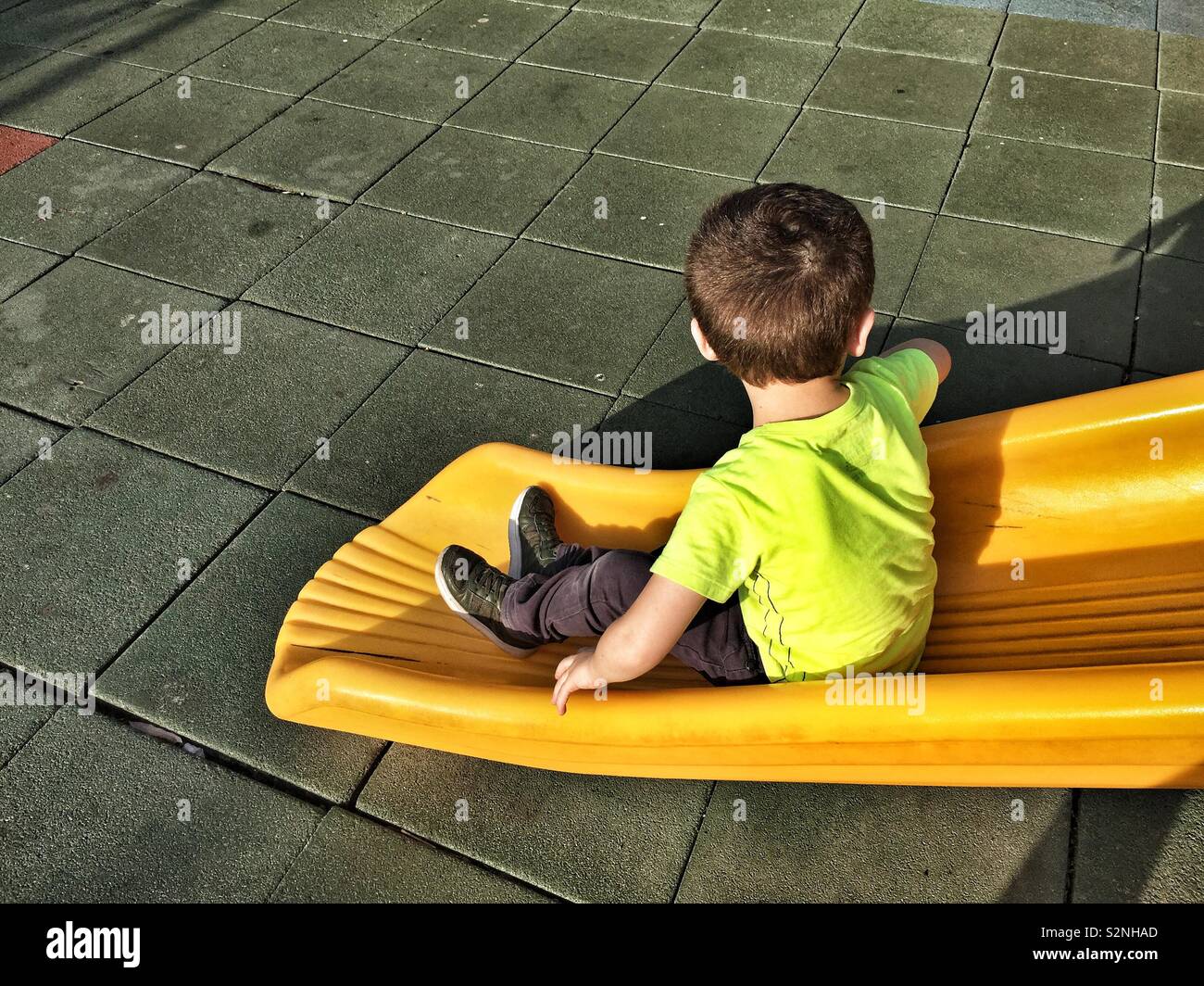 Boy playing on slide in playground Stock Photo - Alamy