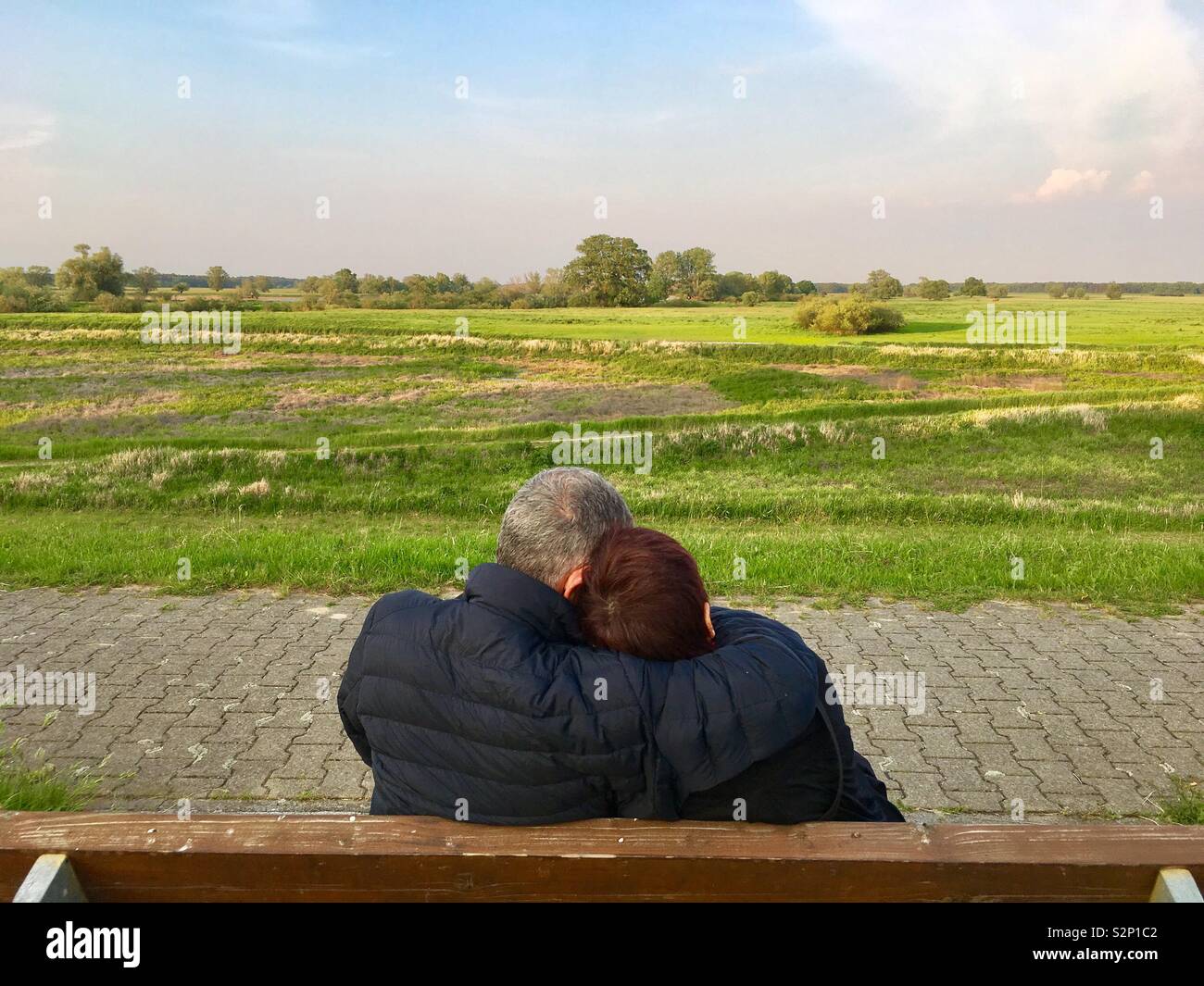 Couple in love sitting on a bench hugging each other Stock Photo - Alamy