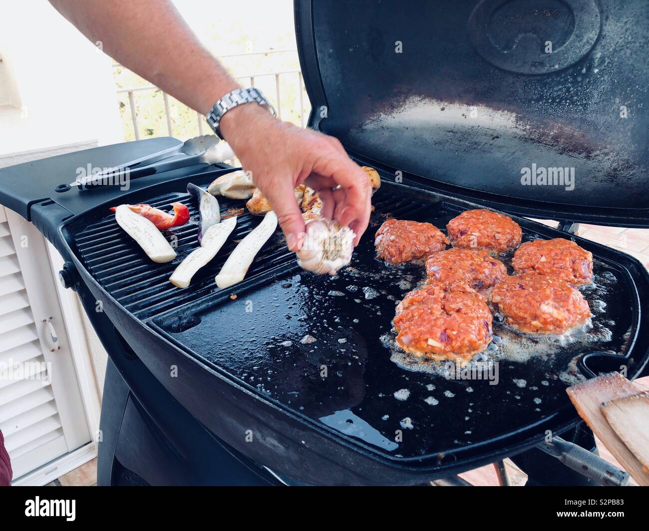 Putting whole garlic on the outdoor grill Stock Photo - Alamy