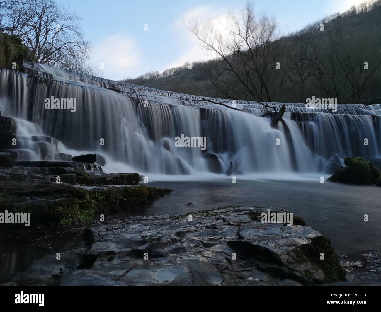 Wide show of waterfall with with rocks in the foreground, using motion ...