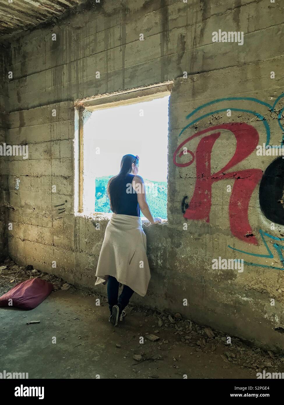 Girl looking out from derelict building Stock Photo - Alamy