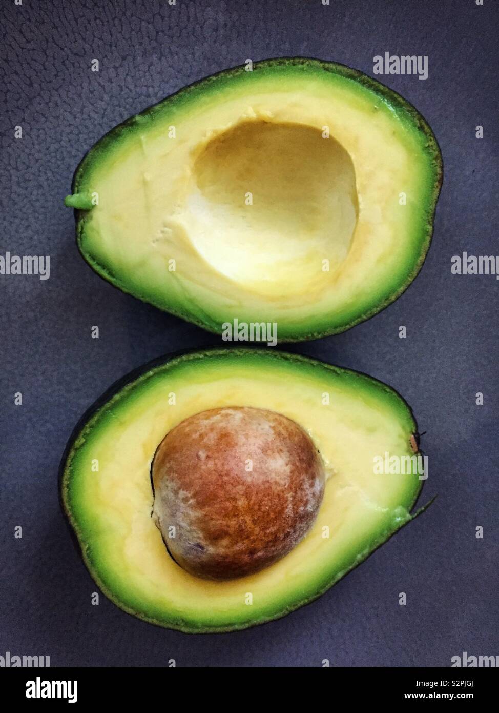 Avocado cut into 2 pieces Stock Photo - Alamy