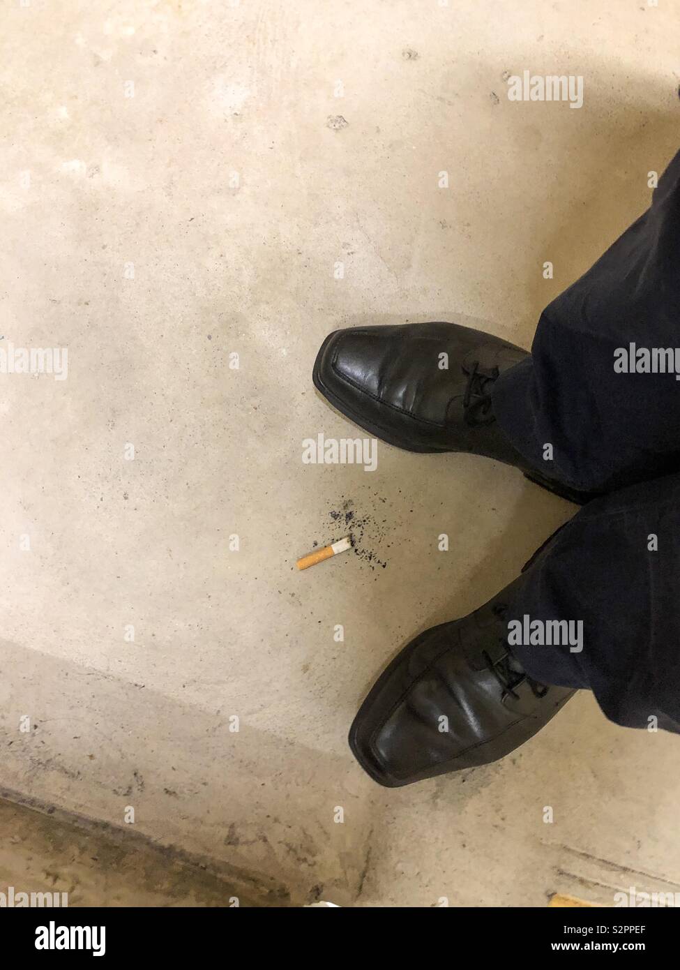 Cigarette butt between a man shoes Stock Photo - Alamy