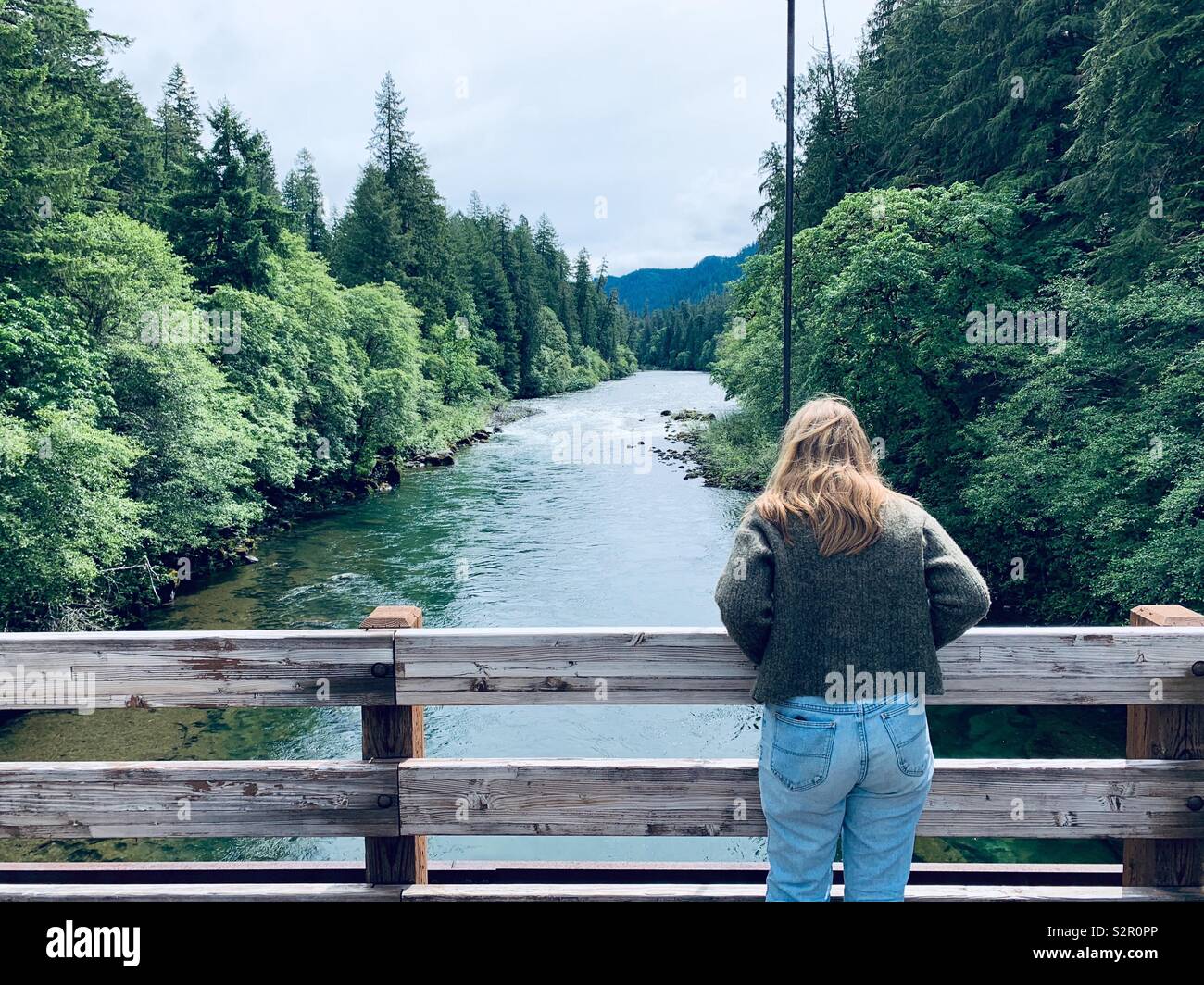 The back of a girl as she looks over a bridge to the river below Stock ...