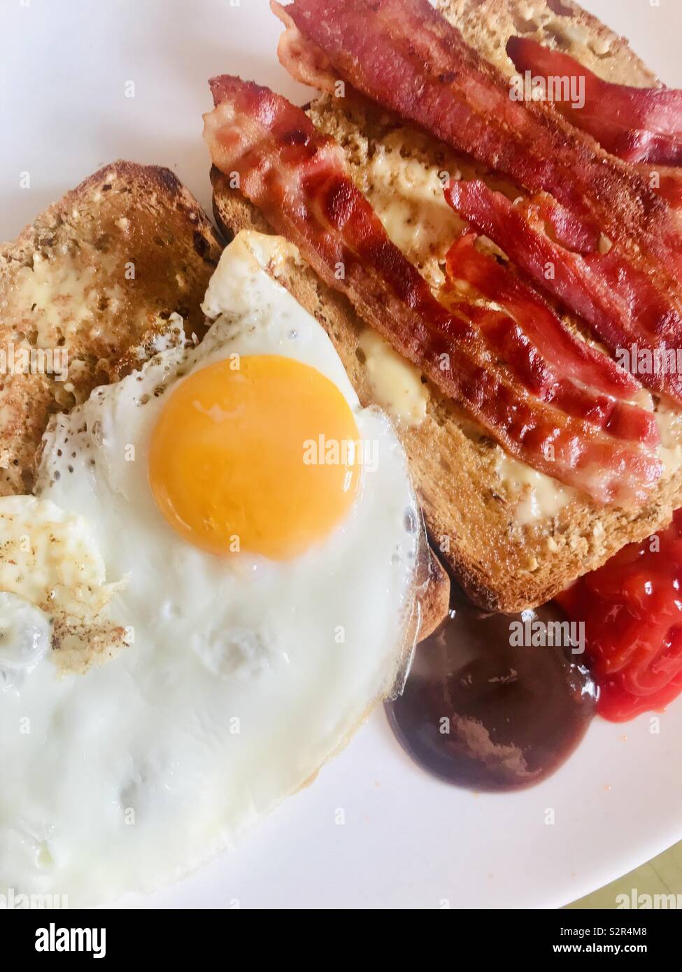 Bacon and egg breakfast on brown toast Stock Photo - Alamy