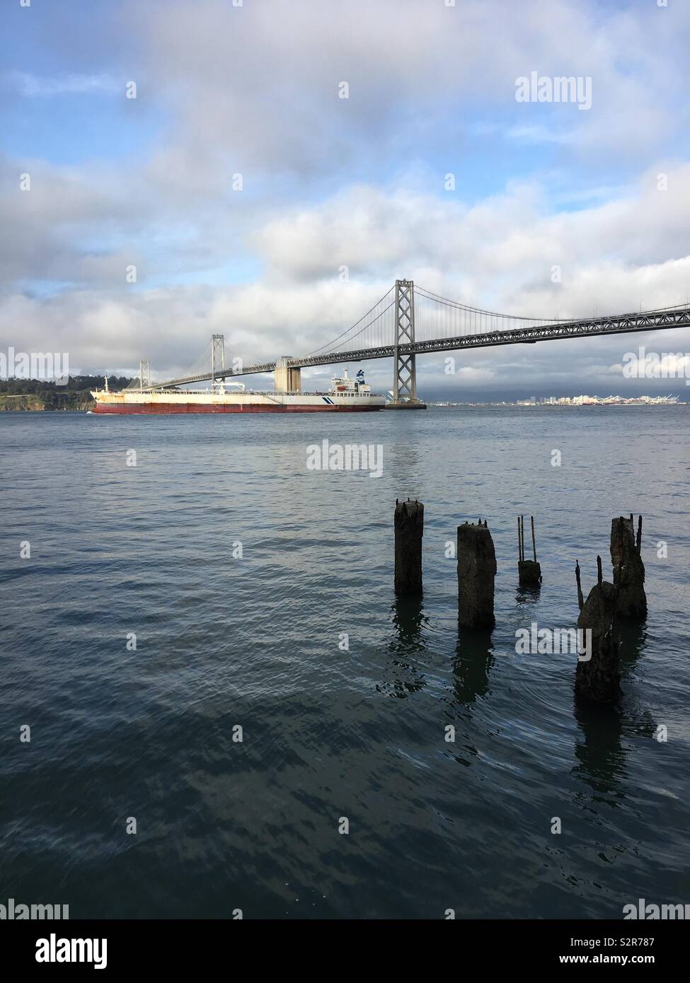 Ship passing under the Bay Bridge, San Francisco Bay with old pilings ...