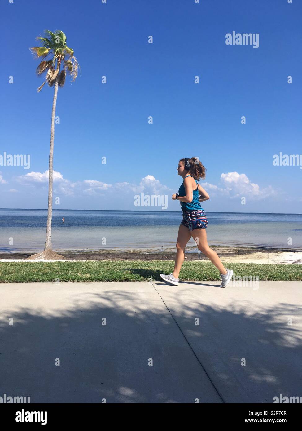 Woman running past palm tree Stock Photo - Alamy