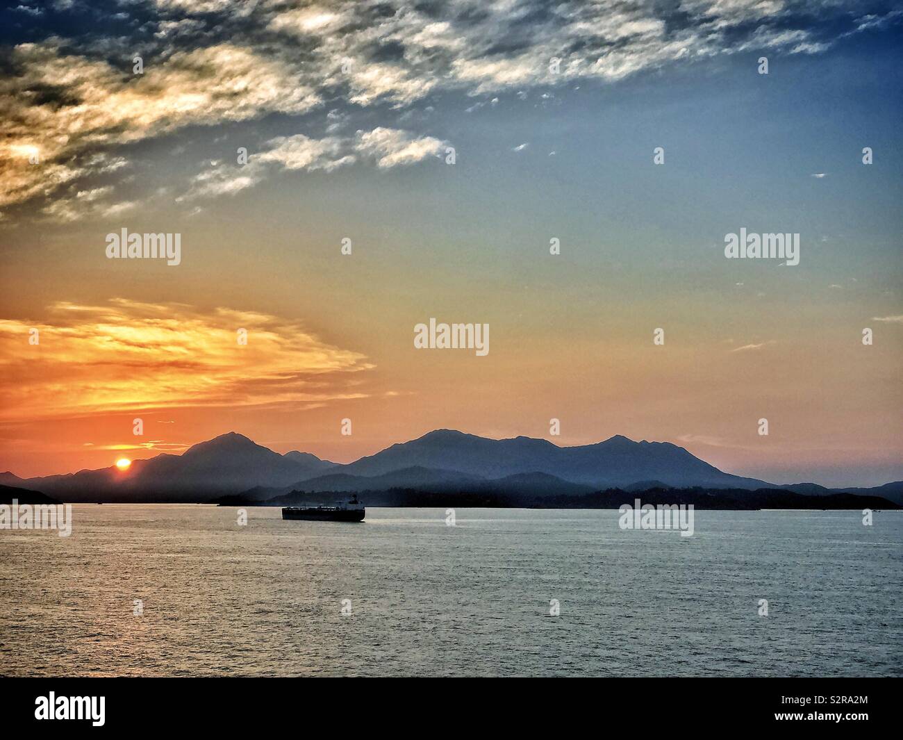 Sunset behind mountains Stock Photo - Alamy
