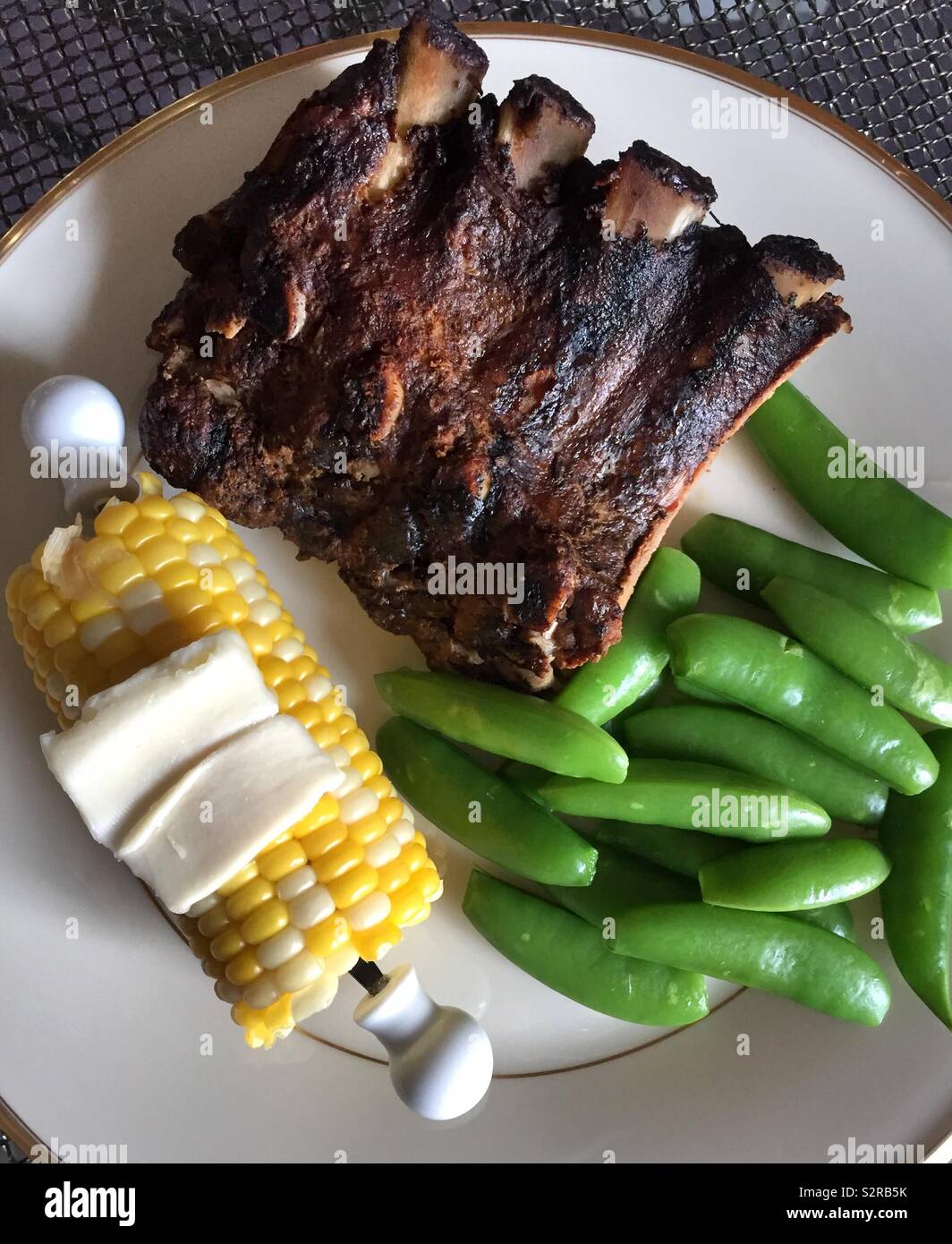 Healthy balanced meal of smoked baby back ribs, corn on the cob and ...