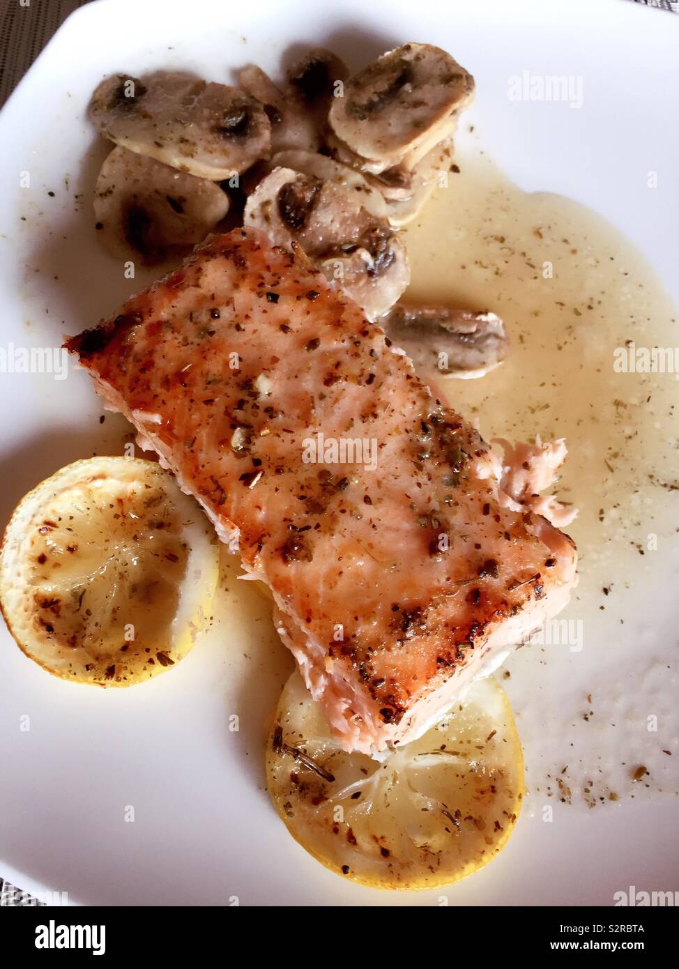 Gourmet entrée of broiled salmon fillet with lemon slices and fresh ...
