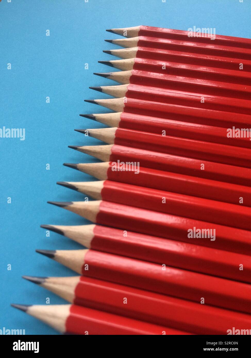 Raw of red graphite pencils on blue background Stock Photo - Alamy