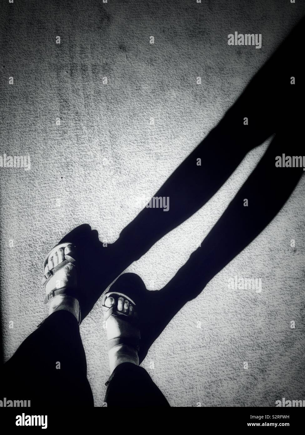 Dark High contrast shadow of female legs and bare feet in sandals on ...