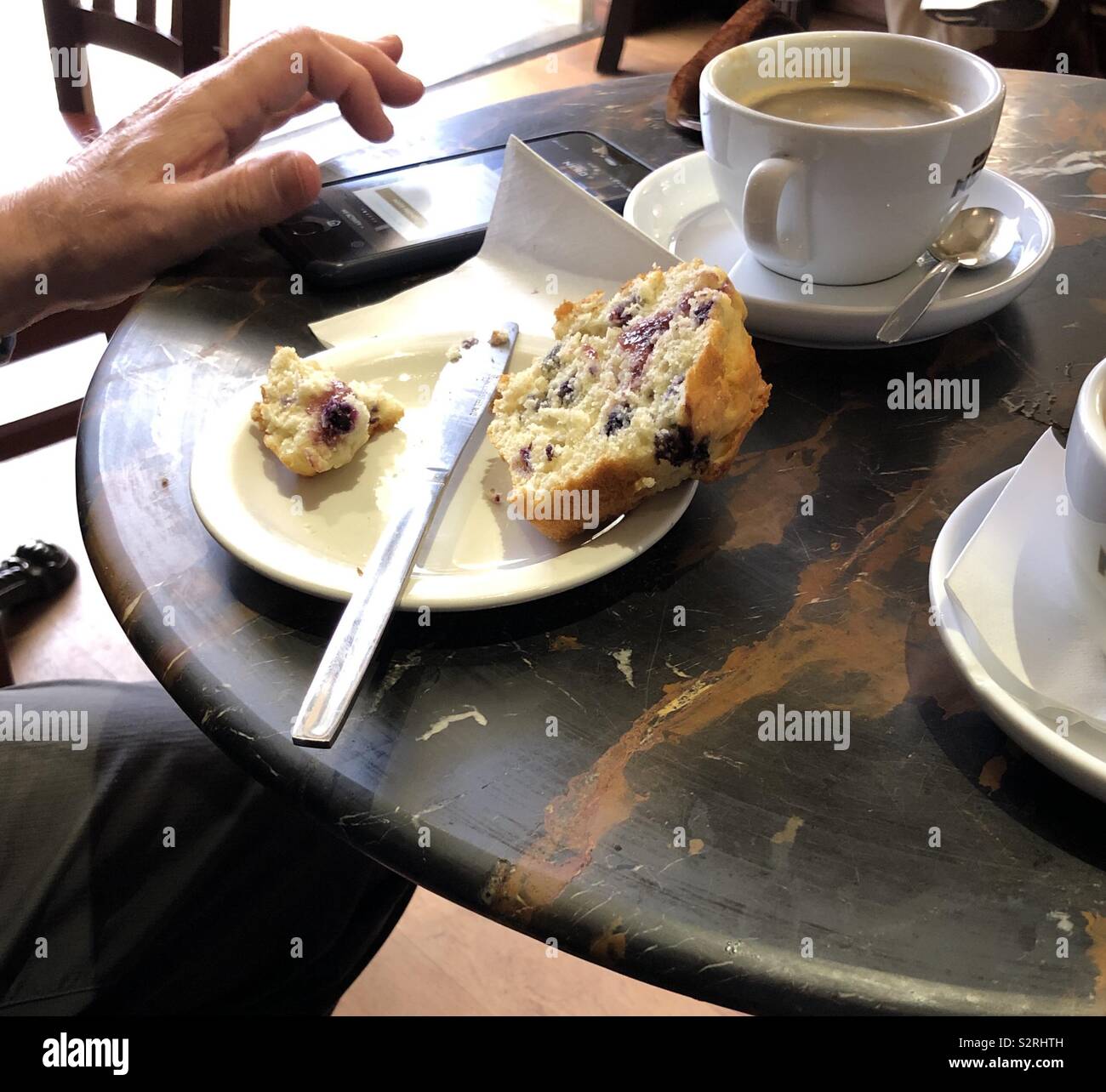 Man having coffee and a muffin and using iPhone in Caffè Nero Stock ...