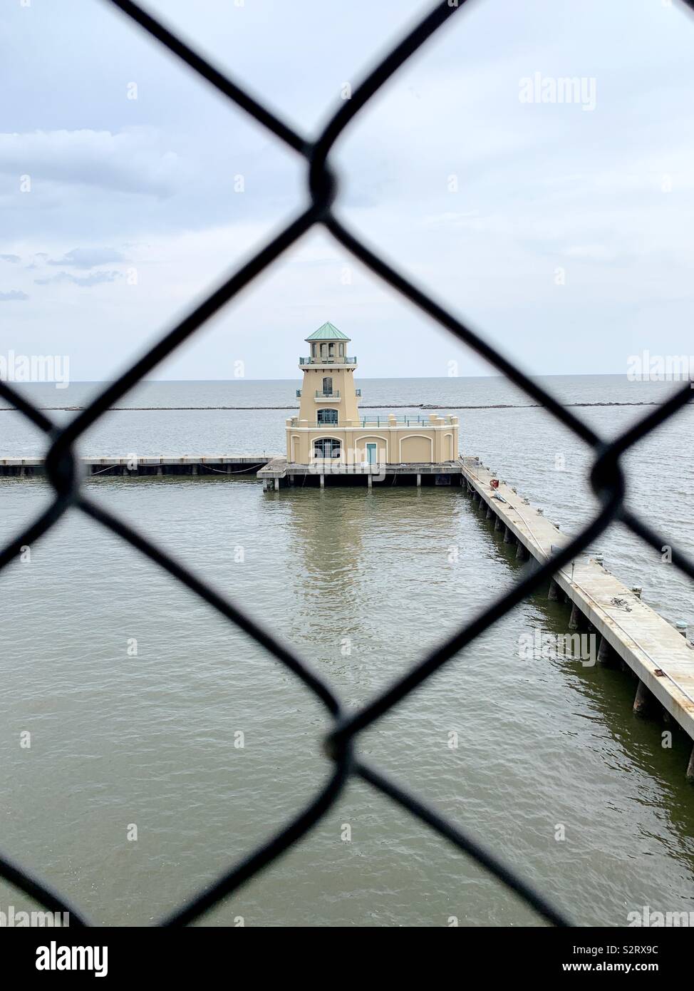 View of lighthouse looking through wire fencing in the ocean Stock ...