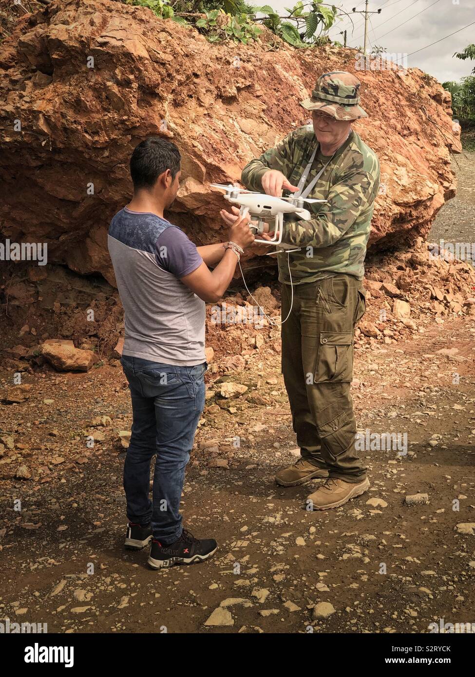 A man and helper preparing a quadcopter drone to take photographs over ...