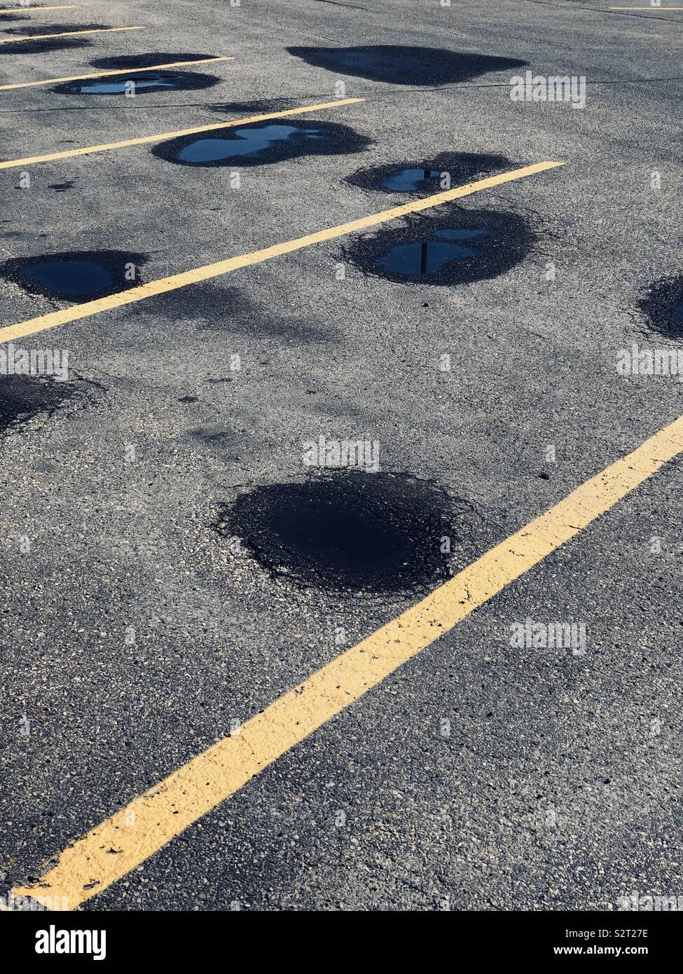 Pothole puddles in a parking lot Stock Photo - Alamy
