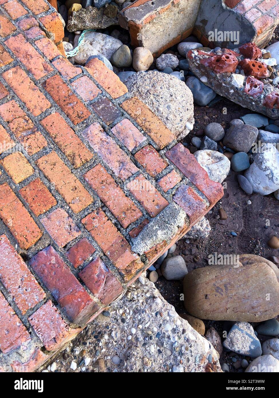 Abstract formed by bricks, rocks and concrete washed up on a beach ...