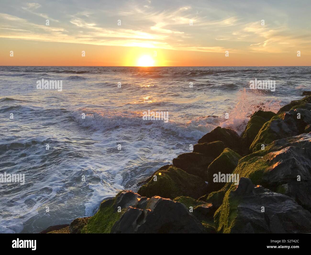 A calm morning at the beach. Sunrise coming up over the ocean with ...