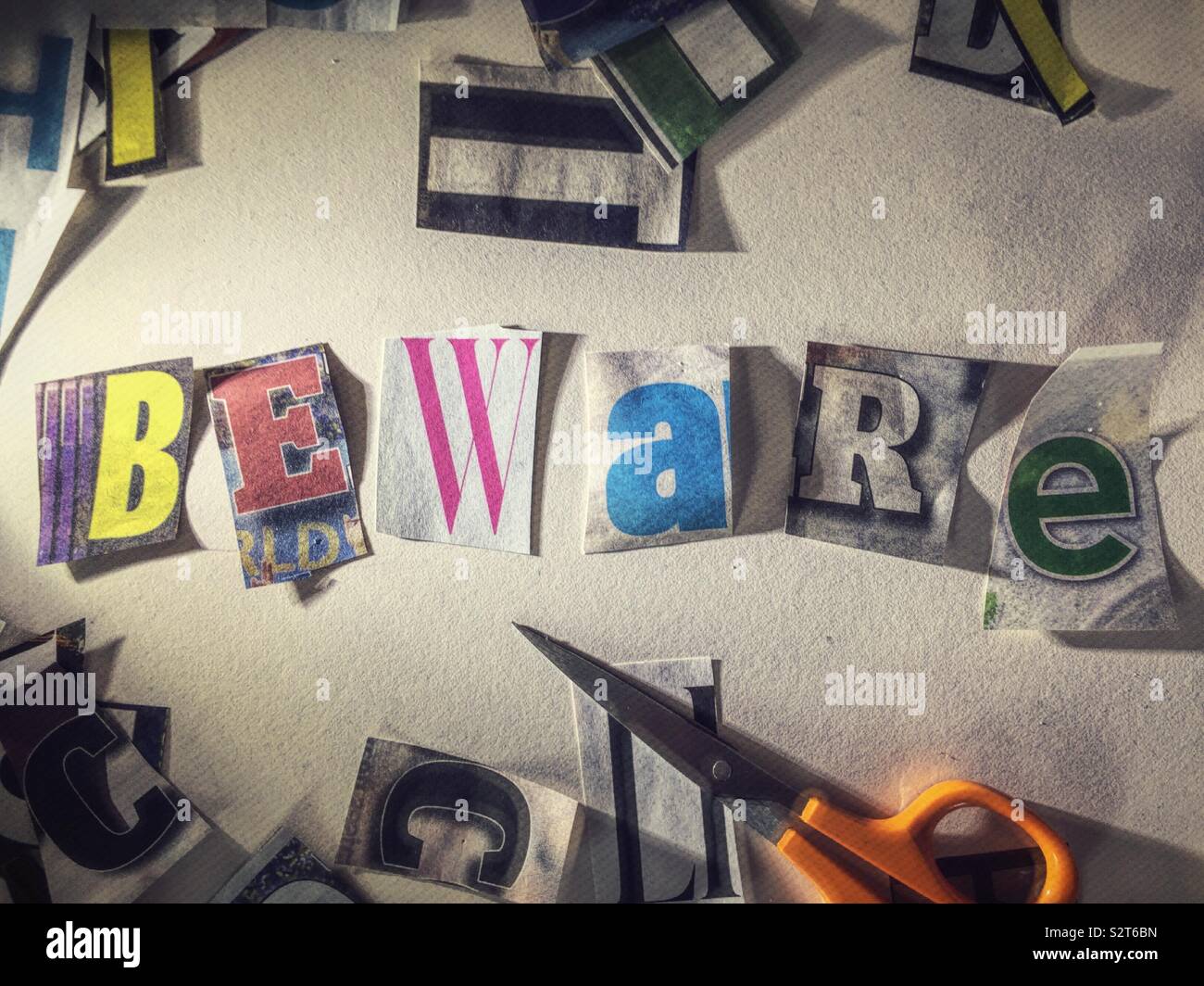 The word beware spelled out on a white countertop in ransom note style ...