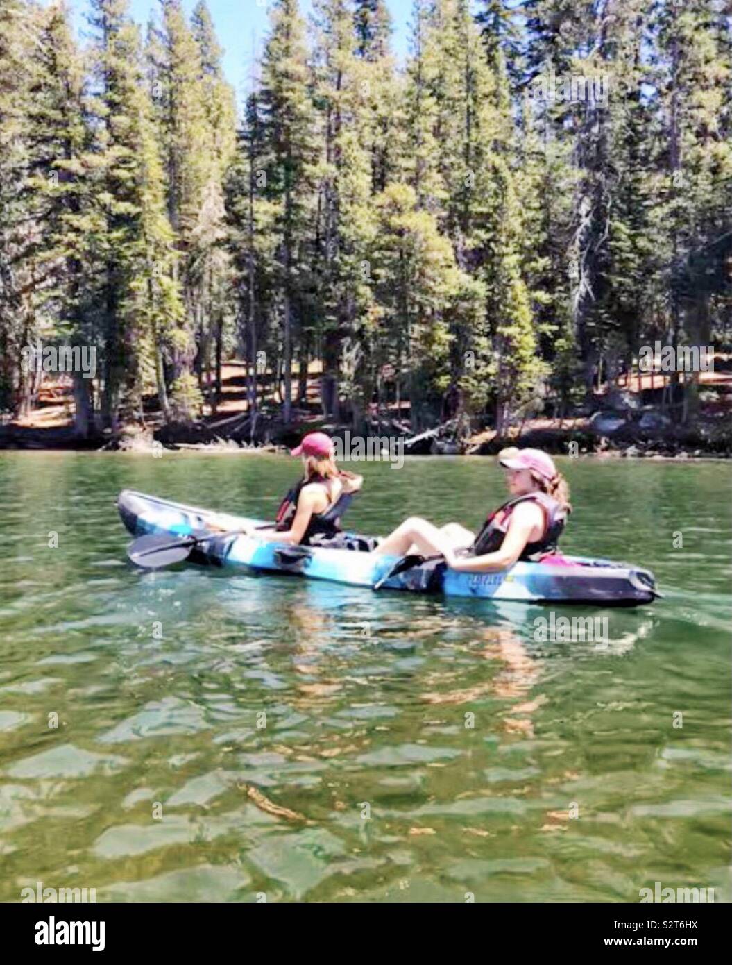 Northern California, two girls kayaking in the green and golden water ...