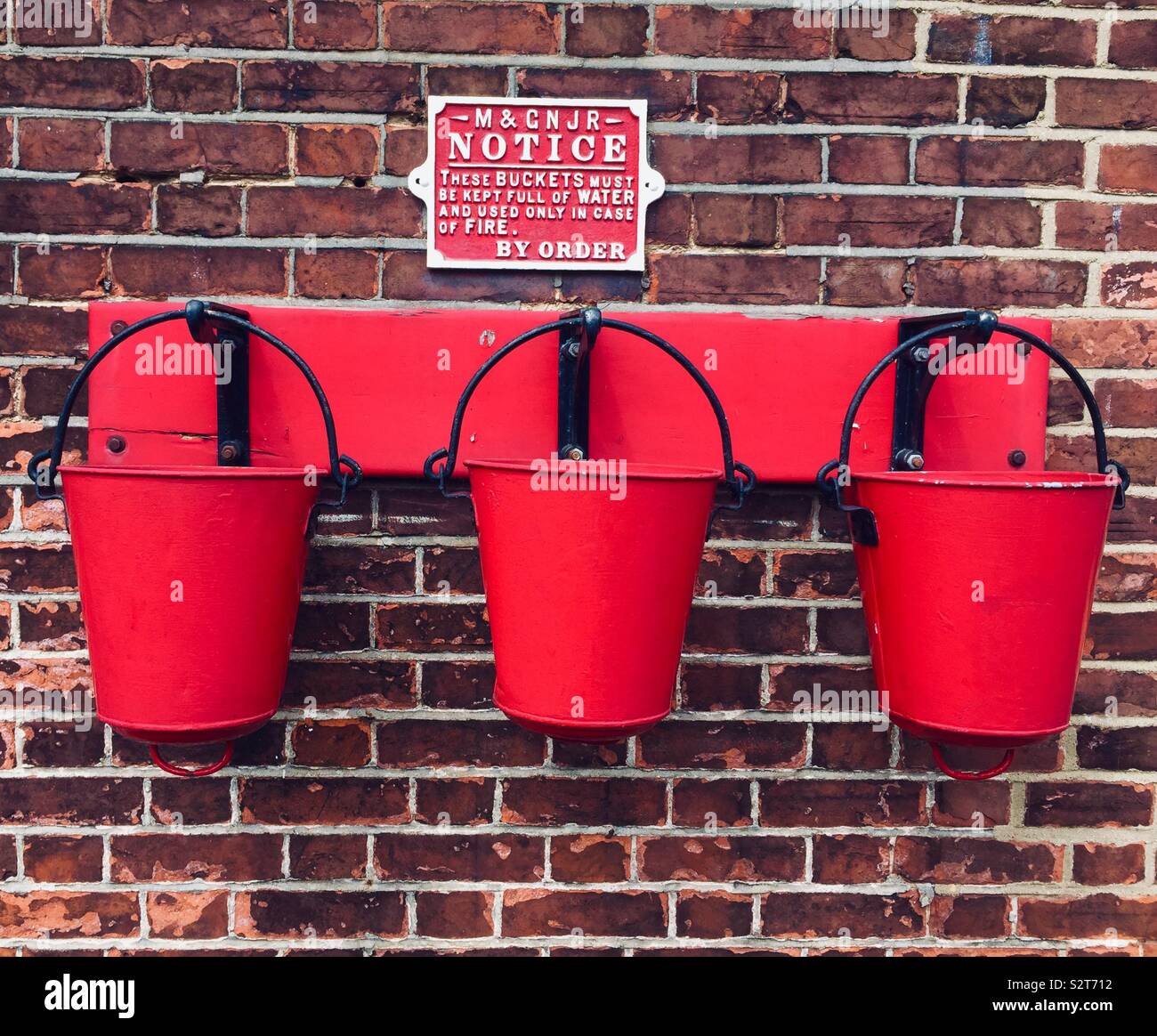 Three vibrant red Fire buckets hanging on a wall Sheringham station ...