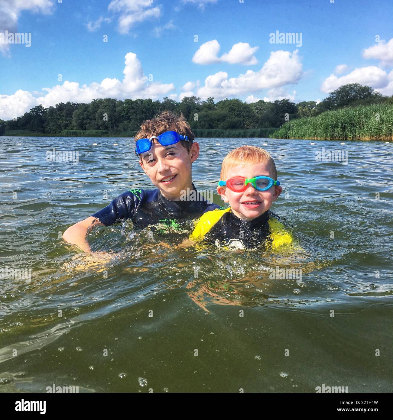 Two brothers ages ten and two swimming at Frensham Great Pond, Surrey ...