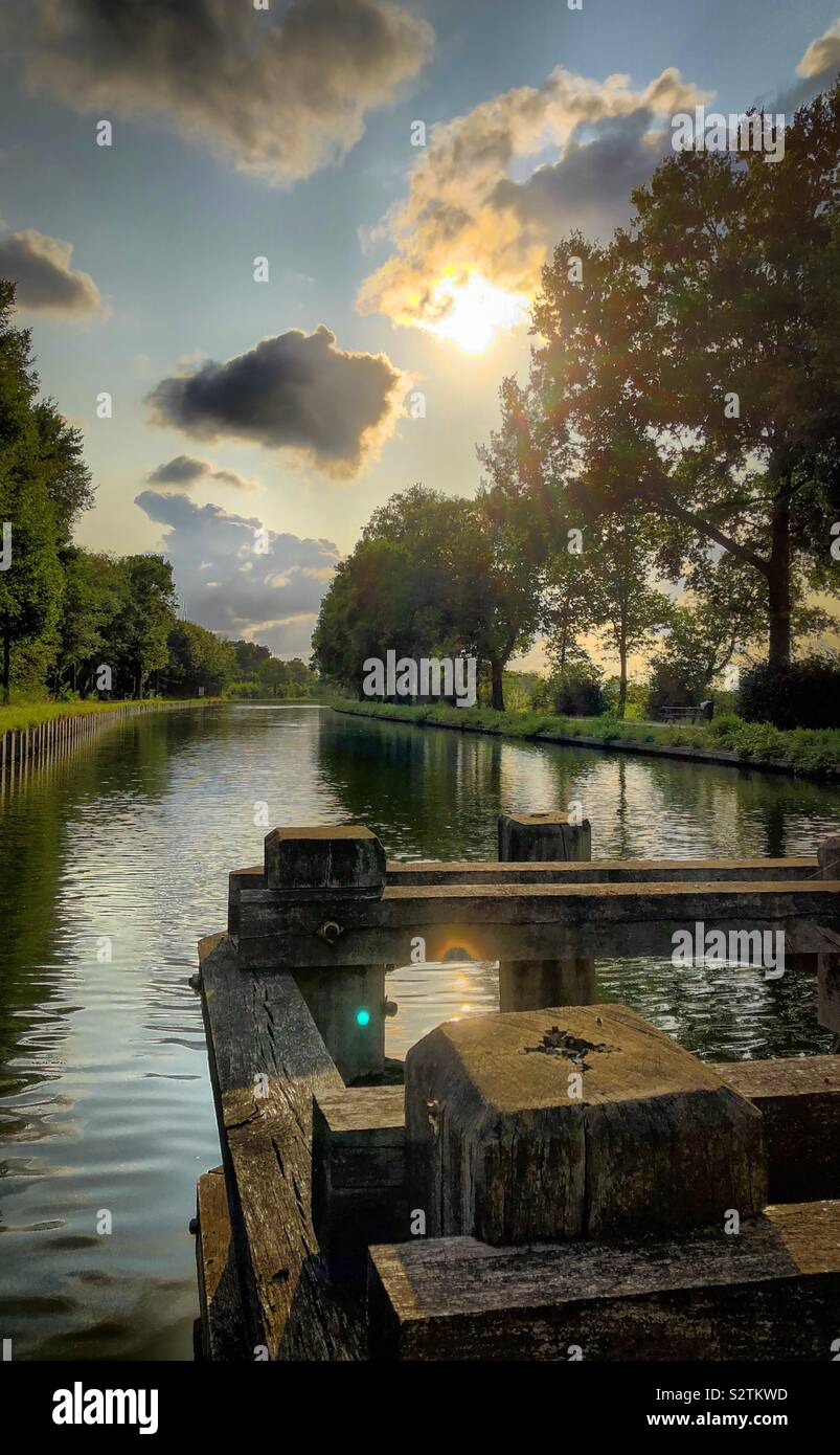 Dramatic sunset or sunrise over a tree lined river landscape as seen ...