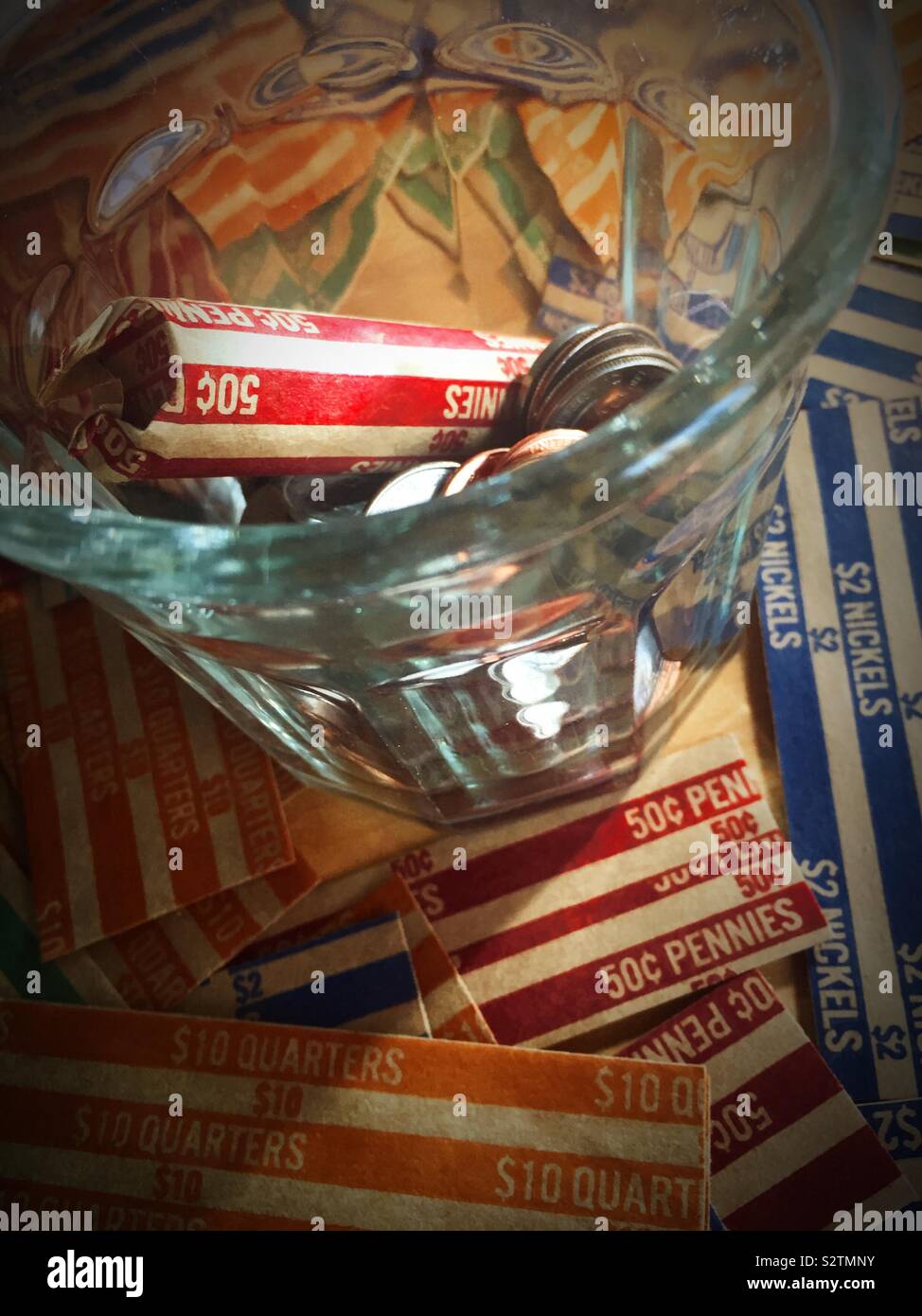 Glass jar filled with loose change and wrapped coins on a bed of coin ...