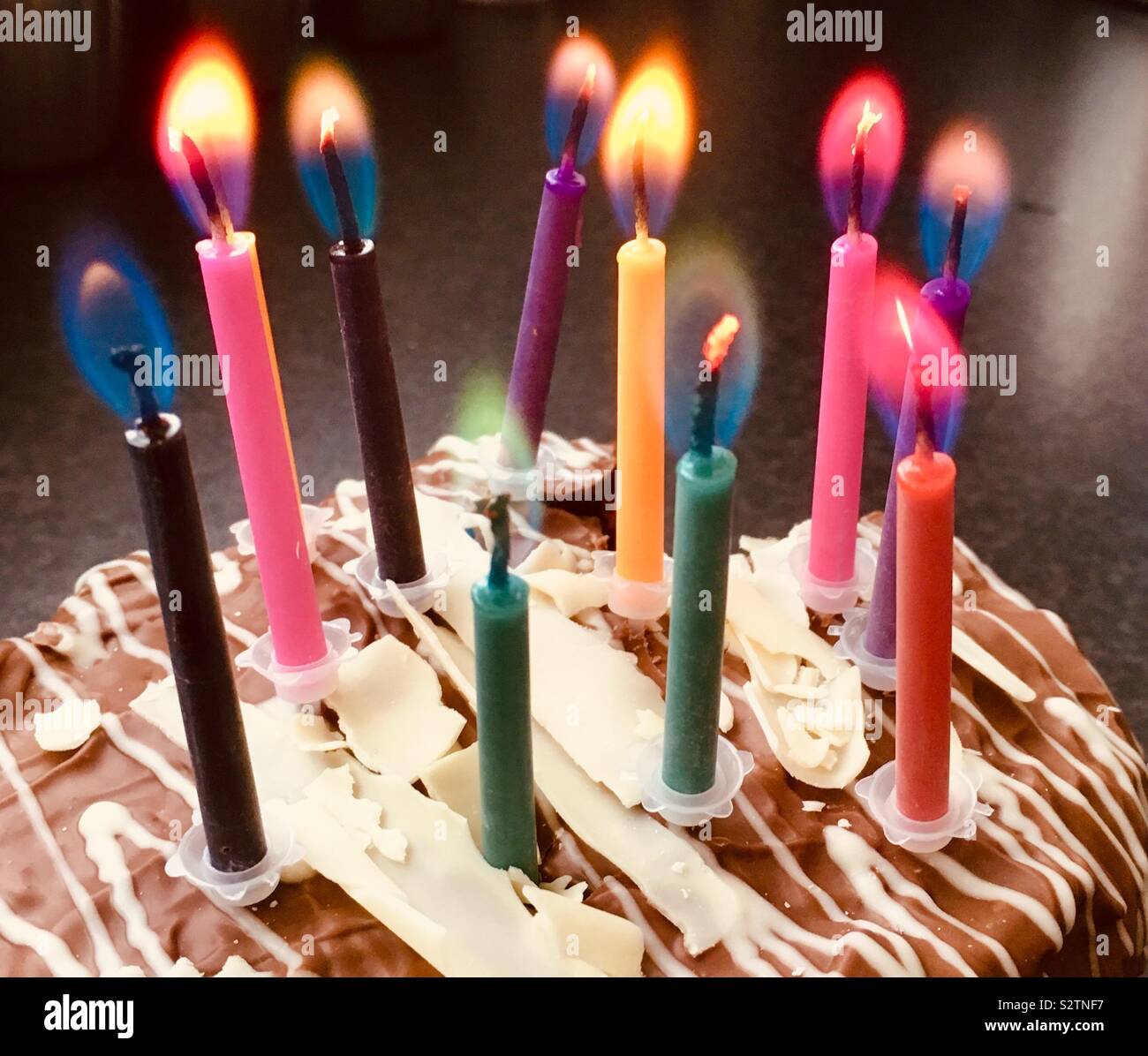 Chocolate cake with multicoloured candles with different coloured ...
